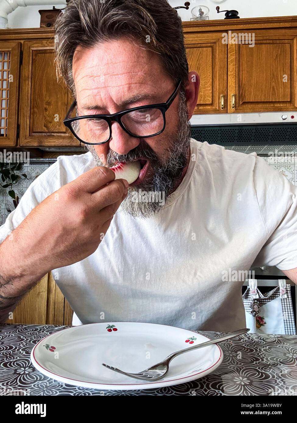 Mature man eating a small piece of fruit in the dish as lunch to eat in ...