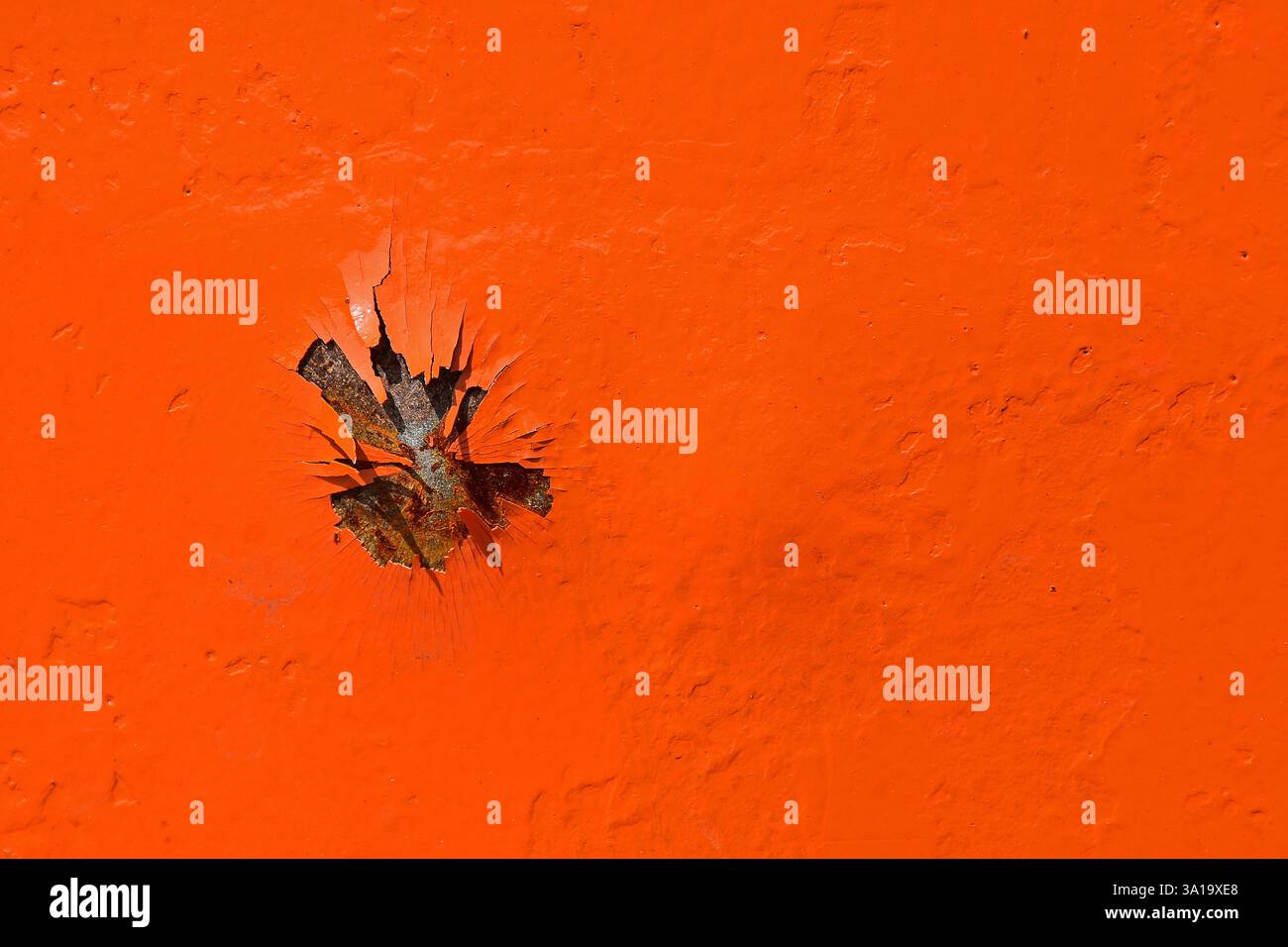 Paint damage to an orange metal wall Stock Photo - Alamy