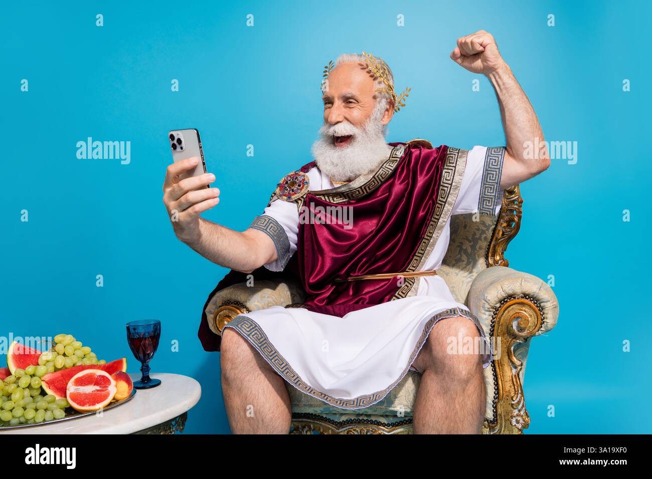 Portrait of delighted rich ancient senator sit throne use phone raise ...
