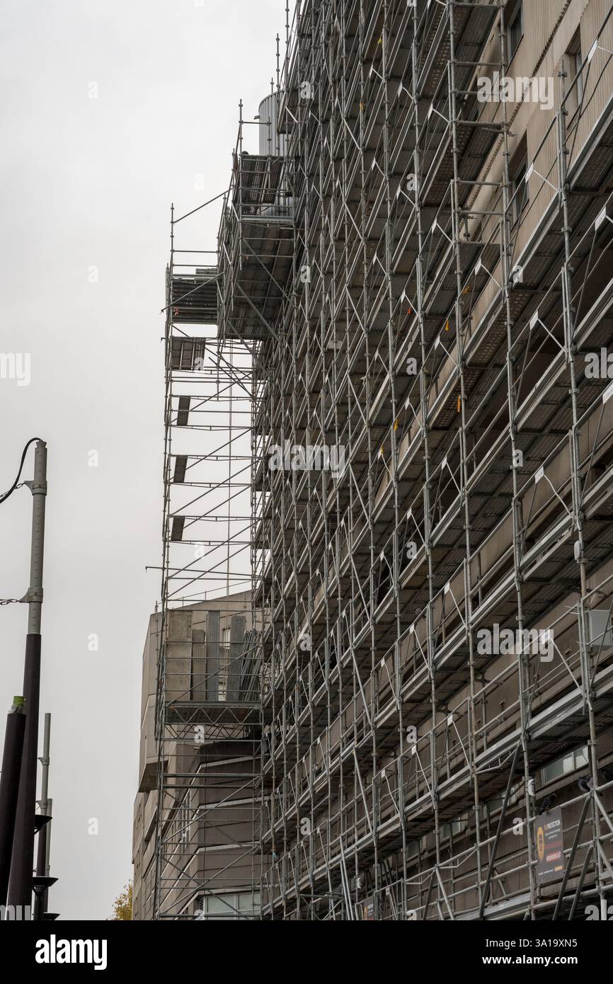 Construction scaffolding surrounds a tall building in a city under ...