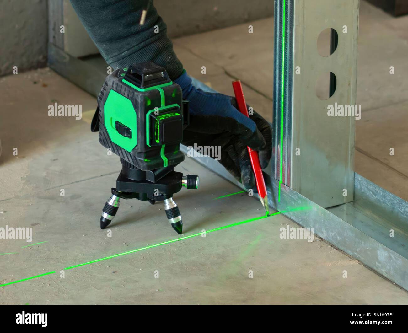 Construction worker using a cross line laser level and marking a red ...