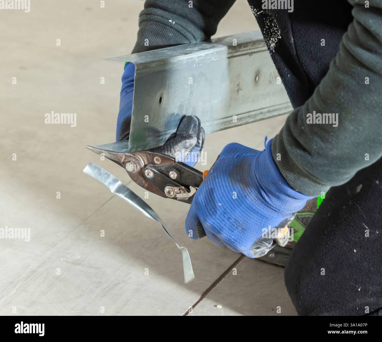 Construction worker wearing protective gloves cutting a metal profile ...