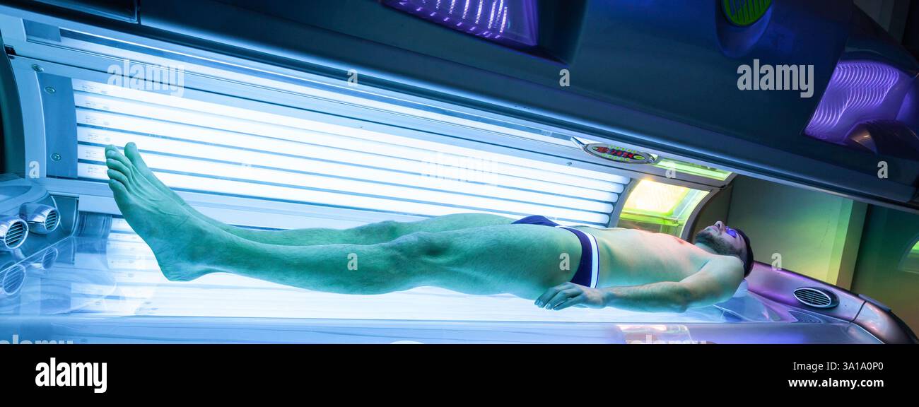 Young Thin Man At Solarium In Beauty Salon. Full tanning bed Stock ...