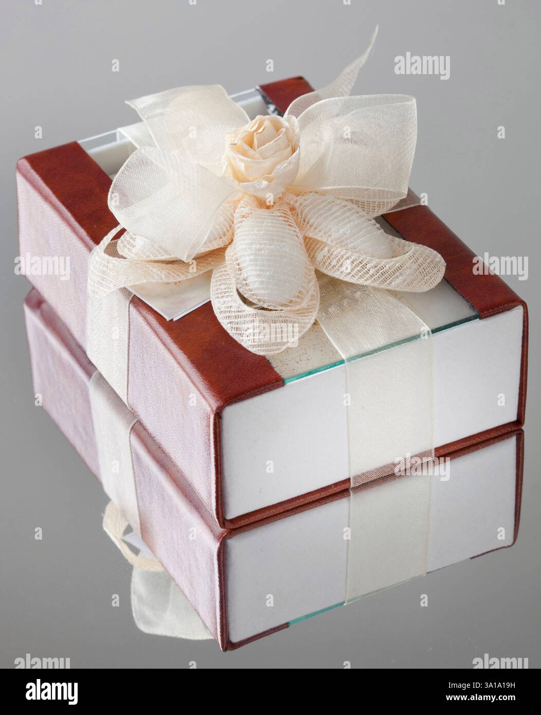 The gift box with a brown cover is wrapped up by a beige tape with a ...