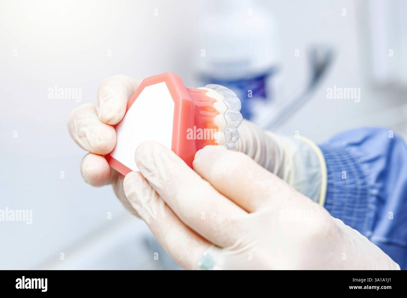 Dentist wearing gloves is holding a teeth model with invisible braces ...