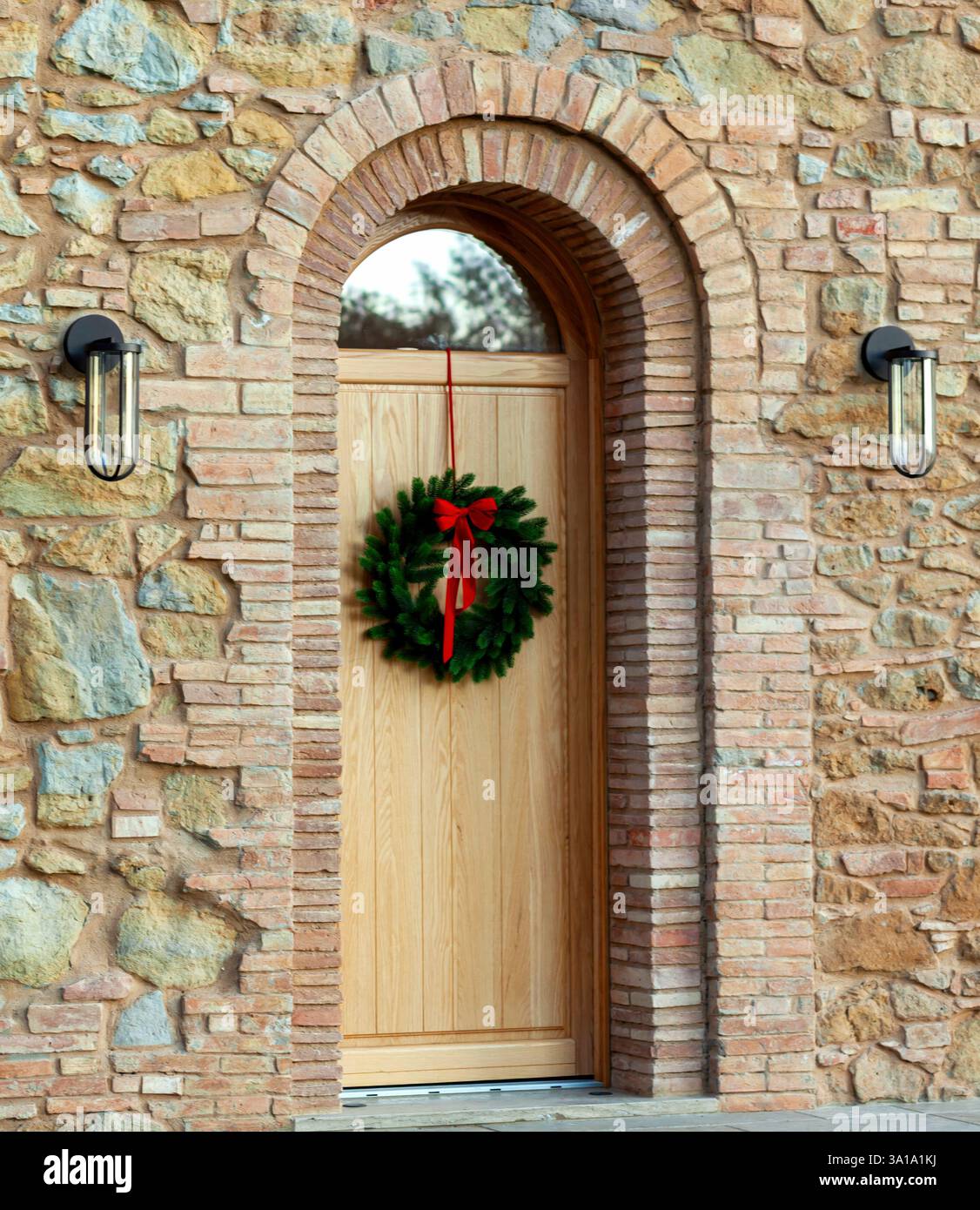 Christmas wreath with red ribbon hanging on wooden door of traditional ...