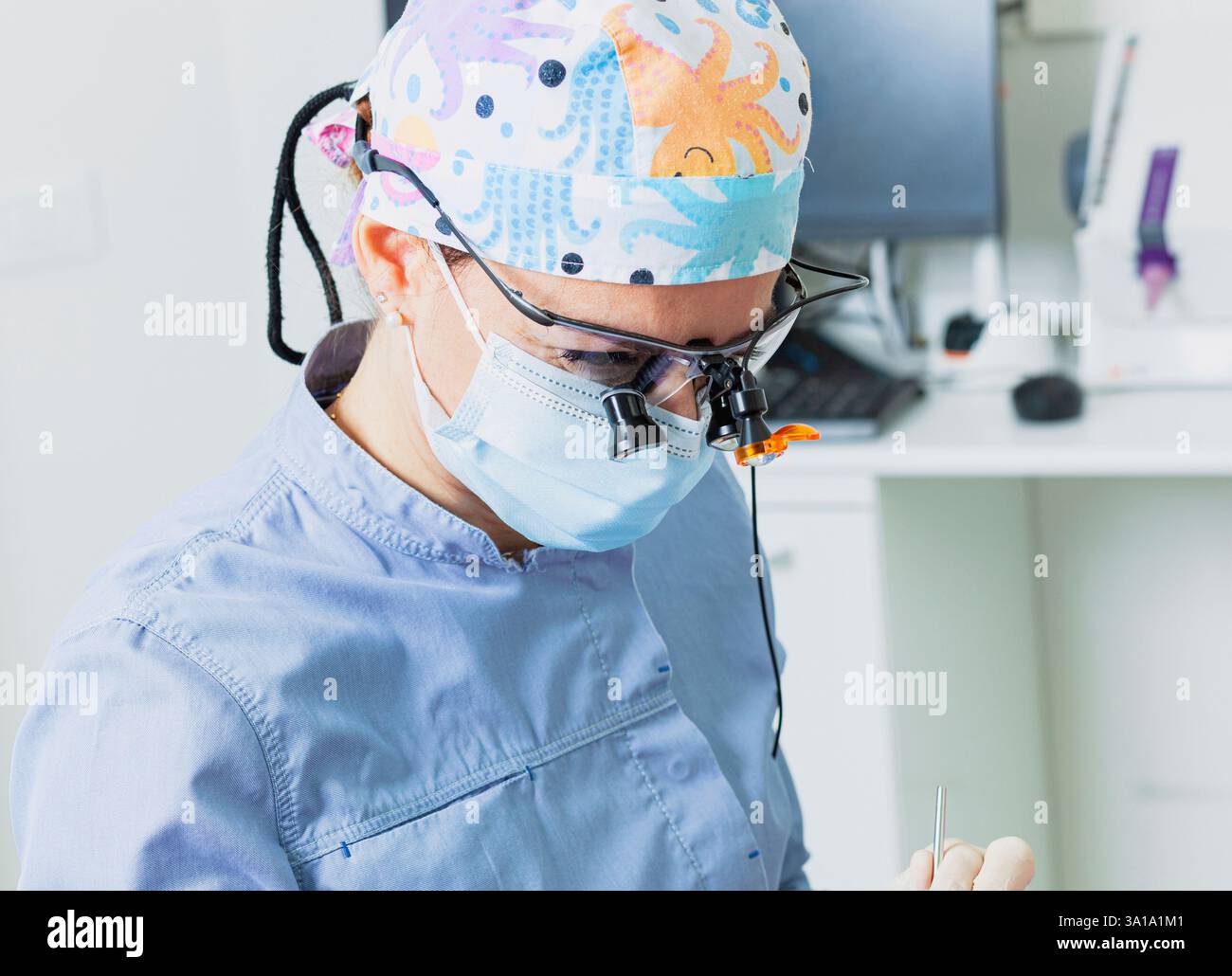 Female dentist wearing surgical loupes and holding dental tools while ...