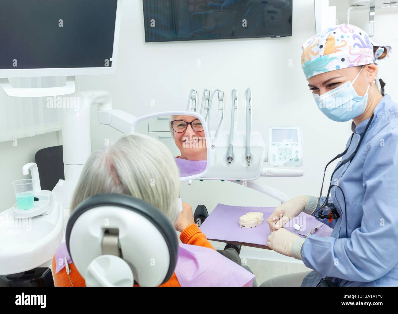 Elderly woman looking at her denture model in dental clinic hi-res ...