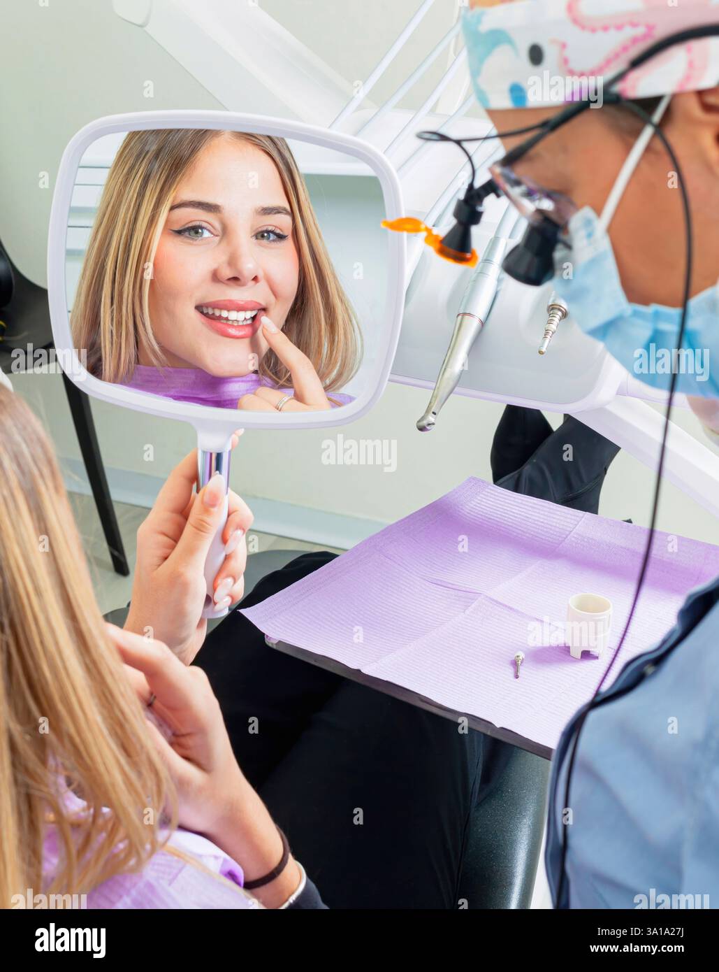 Patient looking at her new smile in the mirror after a dental implant ...