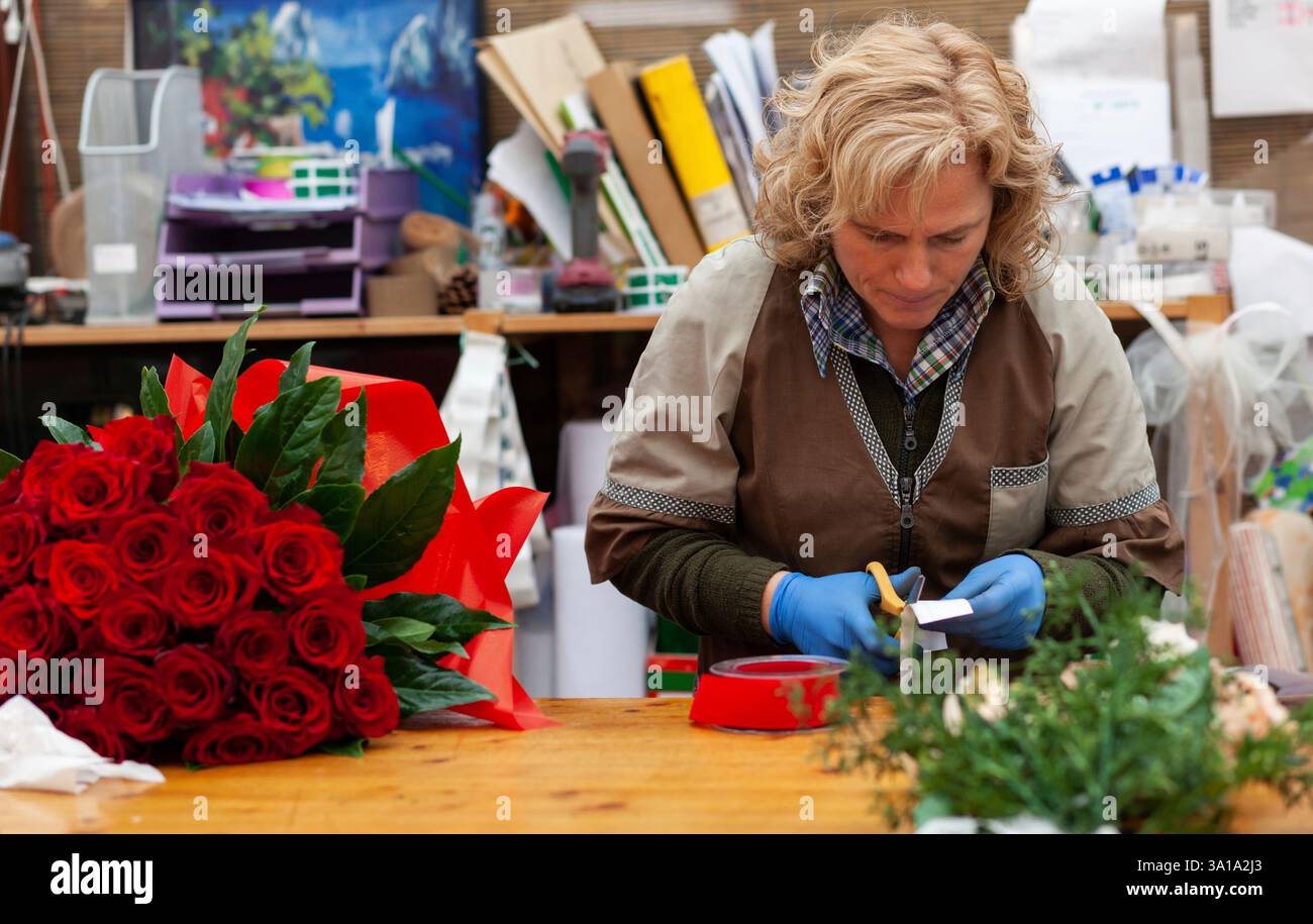 Florist with professional clothing in a nursery. Preparation of a ...