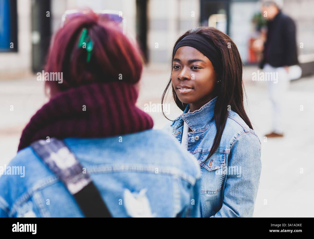 Two friends, of African and Caucasian ethnicity, talk sitting on a ...