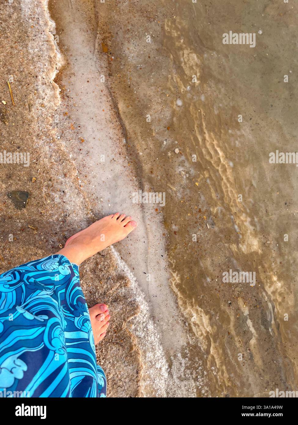 The lake with salt water. Feet on the shore of the Dead Sea Stock Photo ...