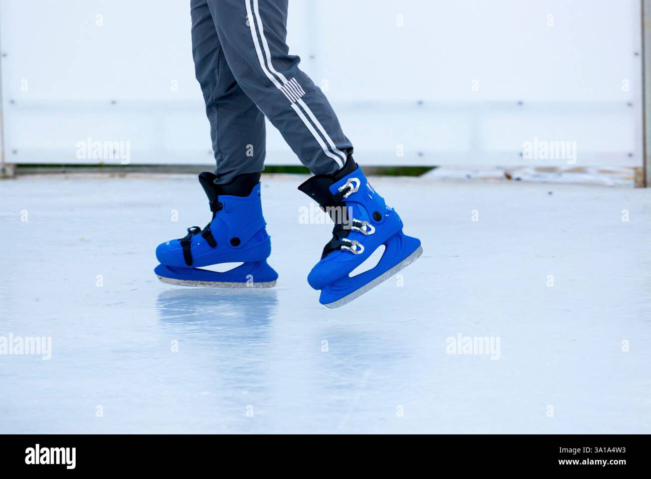 Feet in in blue boots on skates on an open skating rink. Winter ...