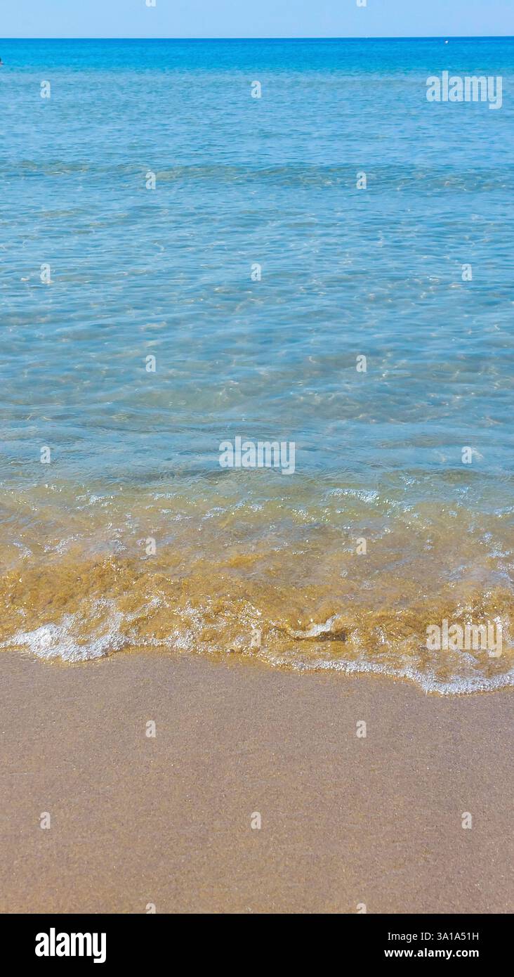 Gentle waves of crystal clear water lapping on the sandy shore of a ...