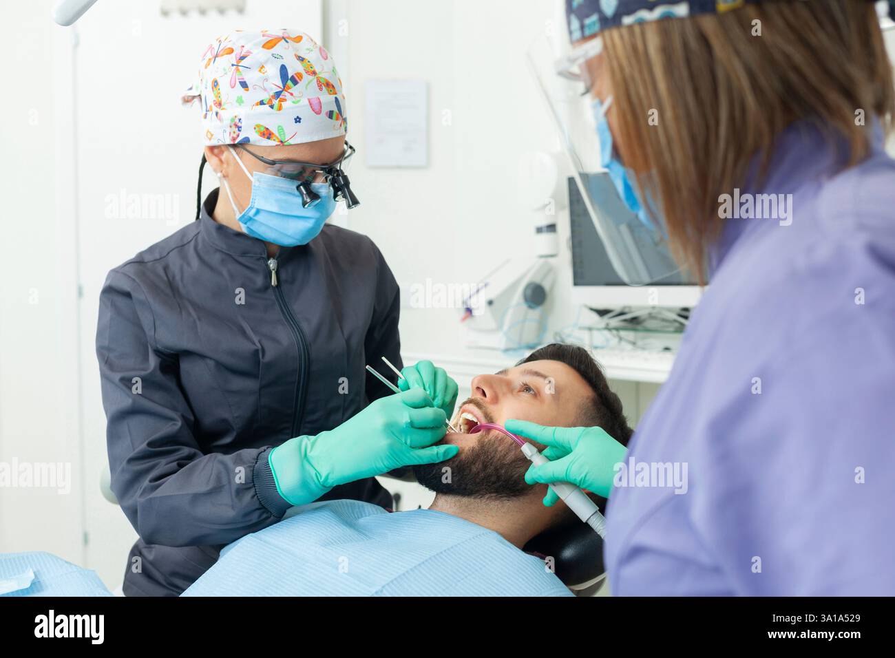 Female dentist examines a man patient in a dental office using ...