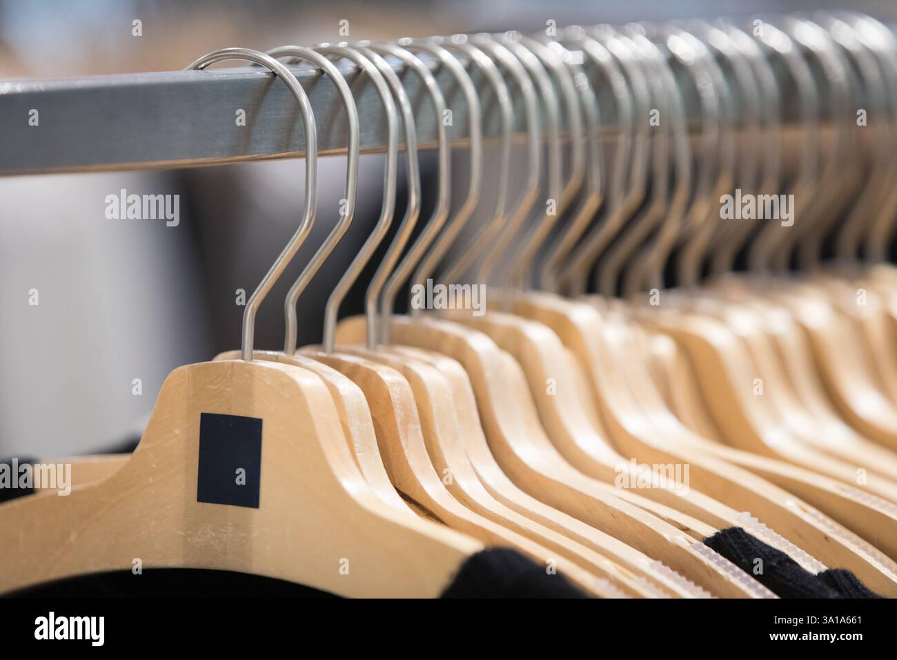 Wooden hangers with clothes on a metal rack in a retail store Stock ...