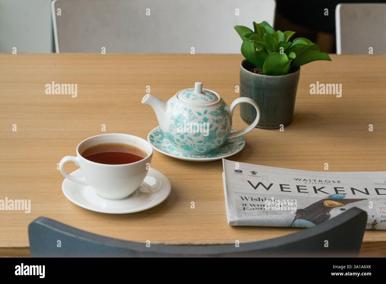 Tea, newspaper, and a plant on a table at Waitrose Stock Photo - Alamy