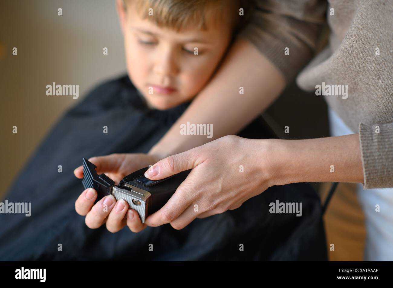 The hairdresser lets the boy see and touch the hair clipper to help him ...
