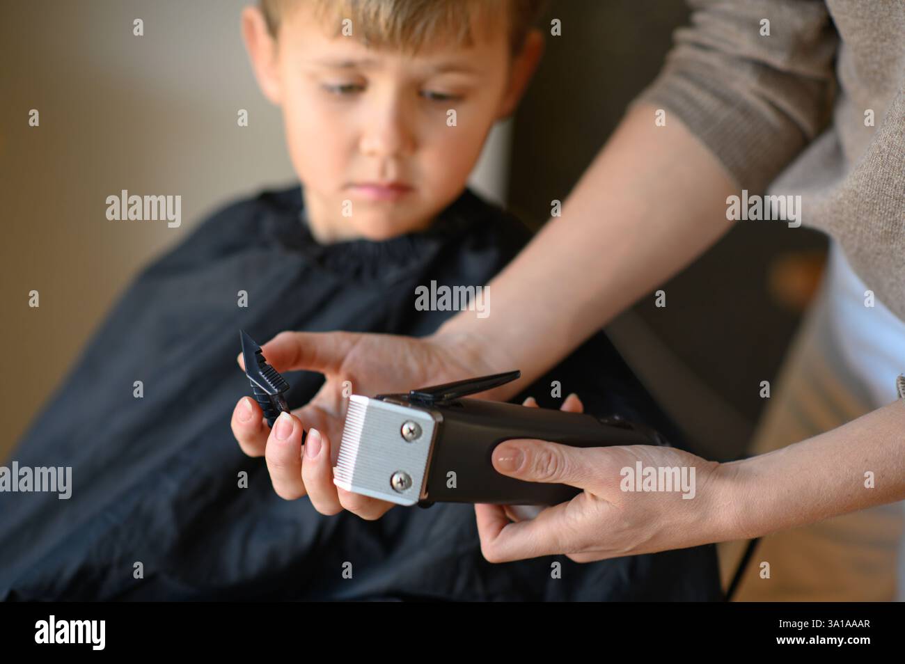 The hairdresser lets the boy see and touch the hair clipper to help him ...