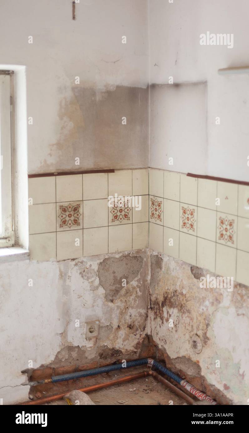 Section of a room with an old damp wall, new copper heating pipes and ...