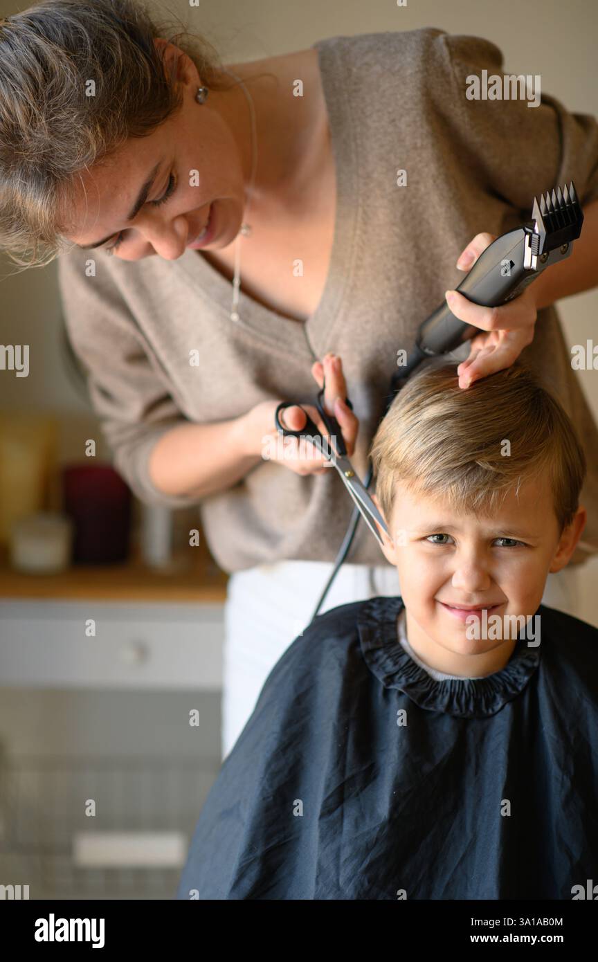 The hairdresser is giving the boy a haircut with an electric clipper ...