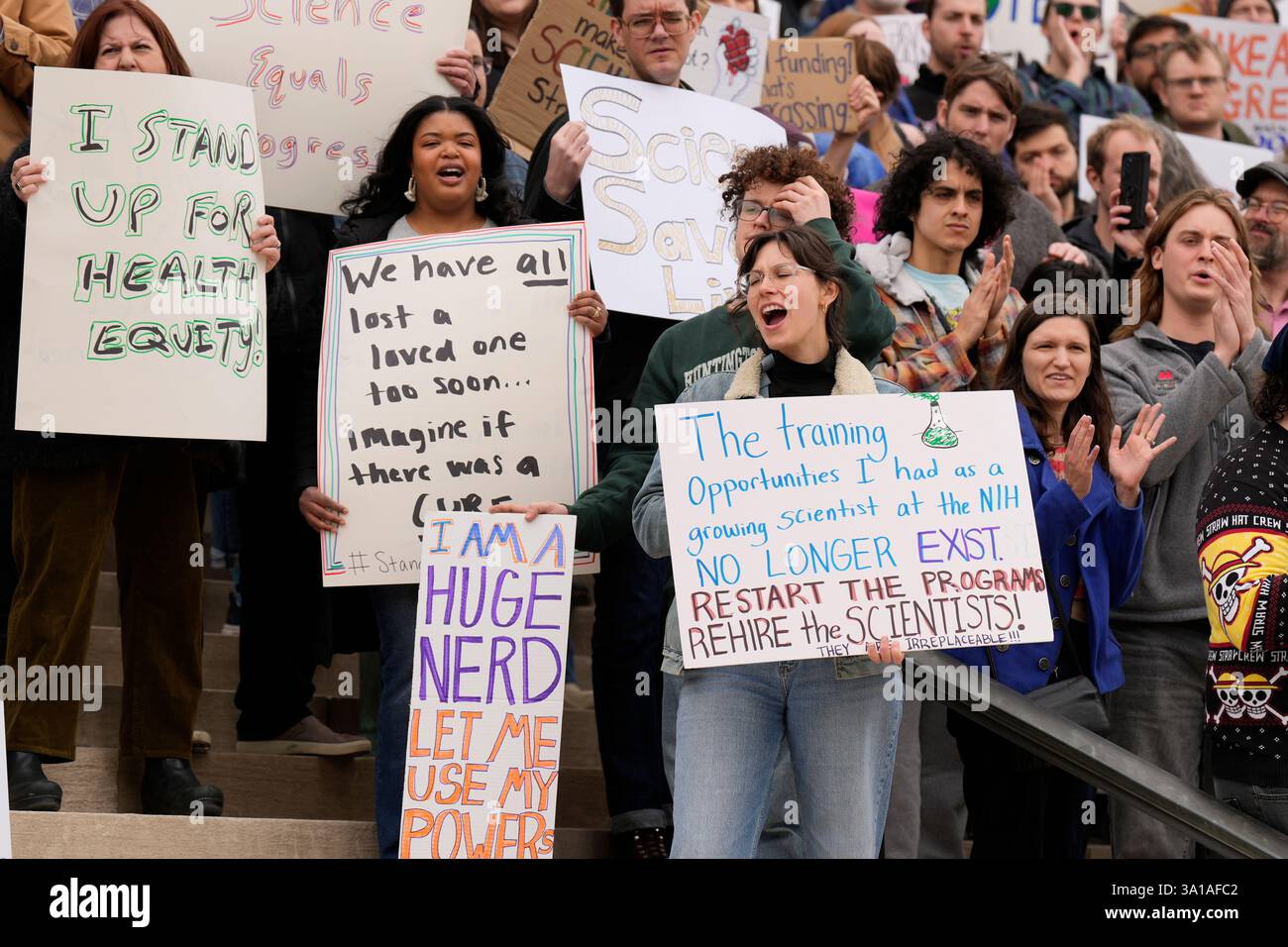 People hold signs during a Stand up for Science rally Friday, March 7 ...