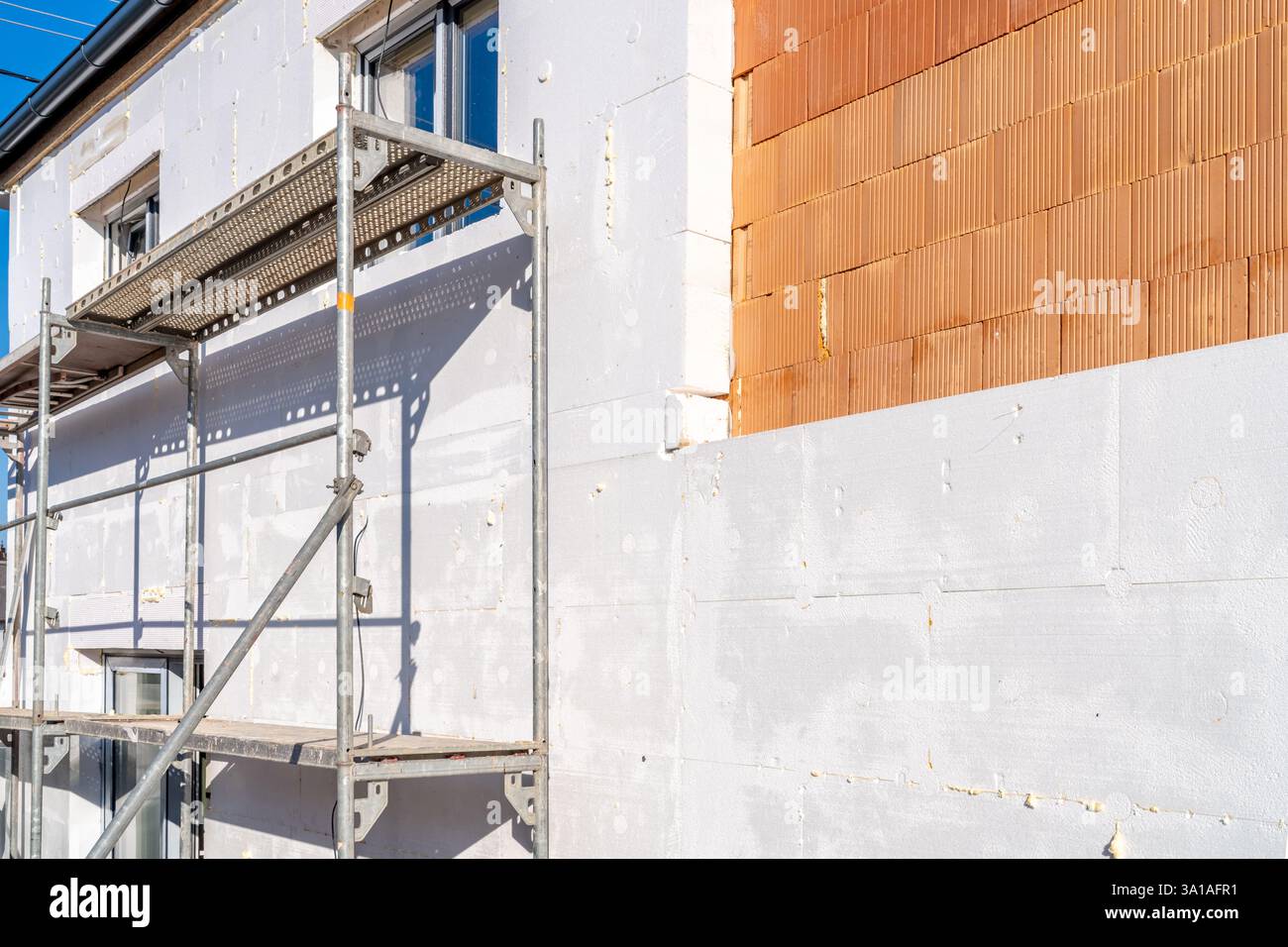 Workers installing external thermal insulation with scaffolding on ...