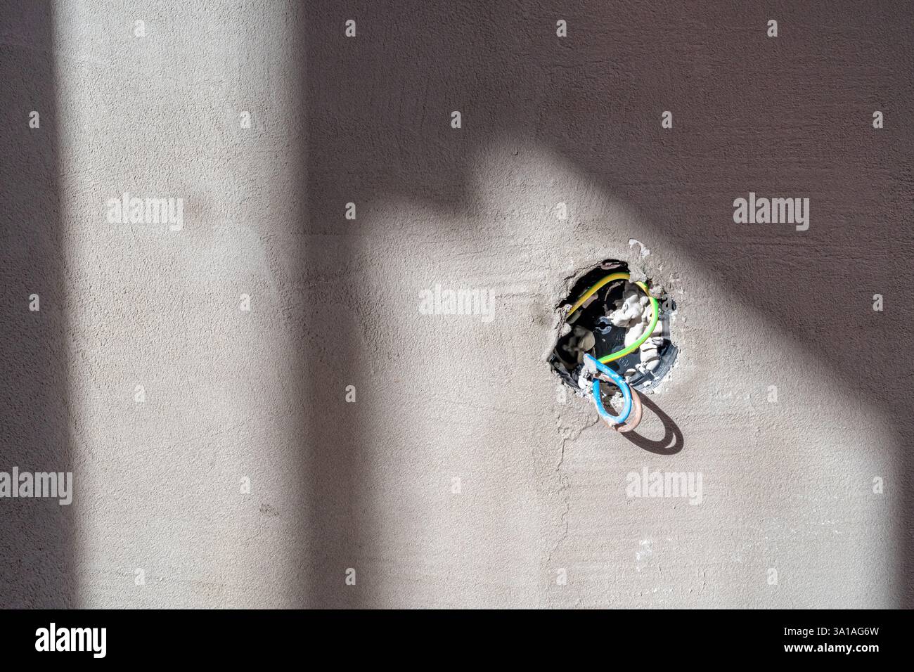 Electrical wiring protruding from hole in concrete wall during ...