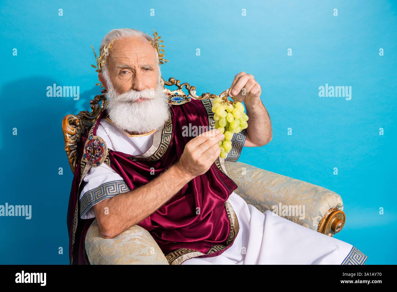 Portrait of antique god man toga costume eat grape sit throne isolated ...
