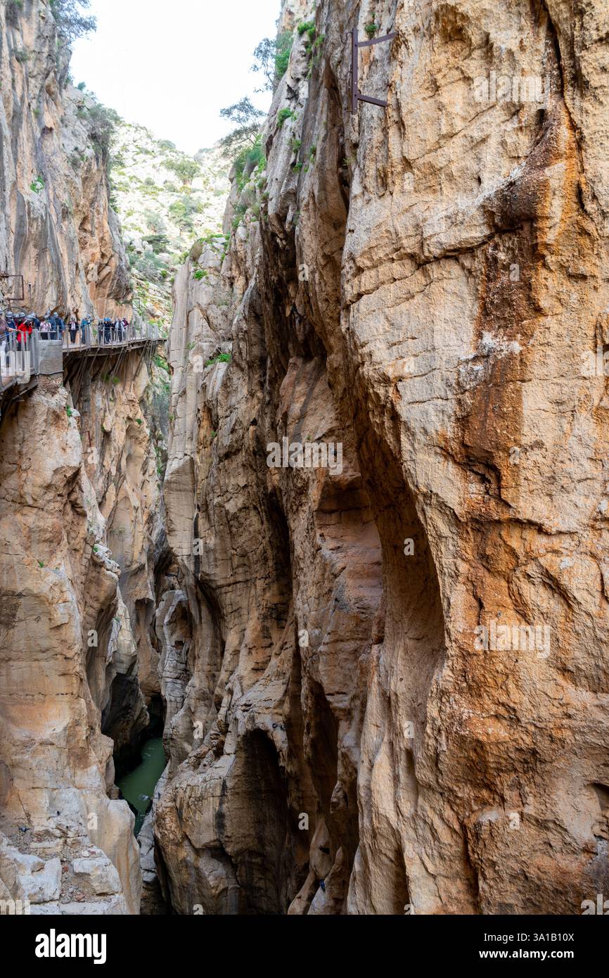 Hikers traverse the narrow wooden walkway clinging to the steep cliff ...