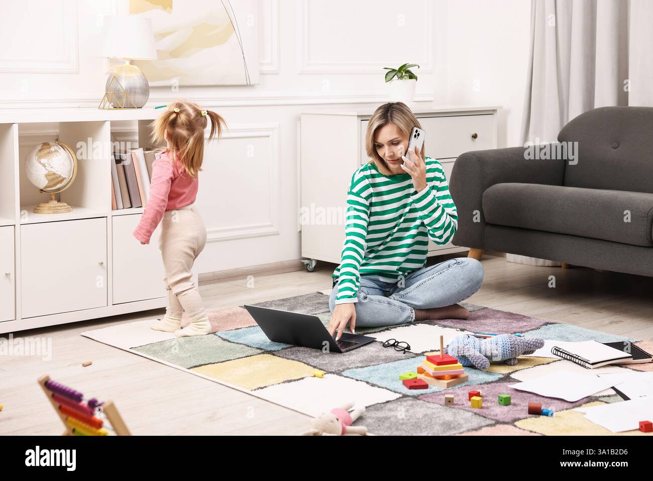 Work at home. Single mother talking by smartphone and her daughter on ...