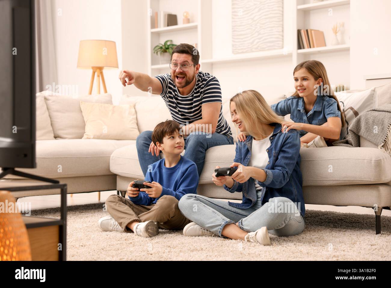 Happy family playing video games in living room Stock Photo - Alamy