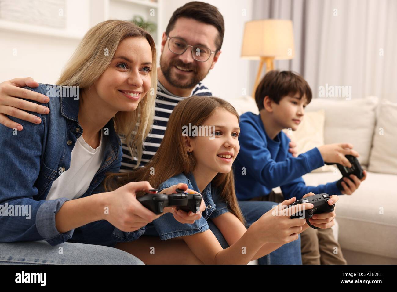 Happy family playing video games on sofa at home Stock Photo - Alamy