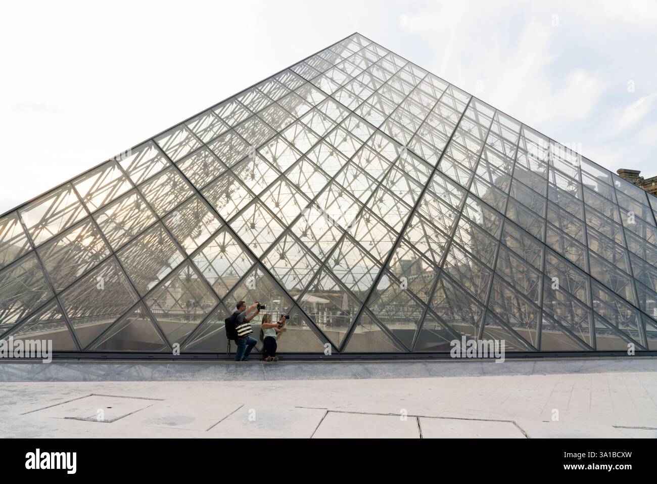 Tourists photograph the Louvre Pyramid in Paris, France. The glass ...