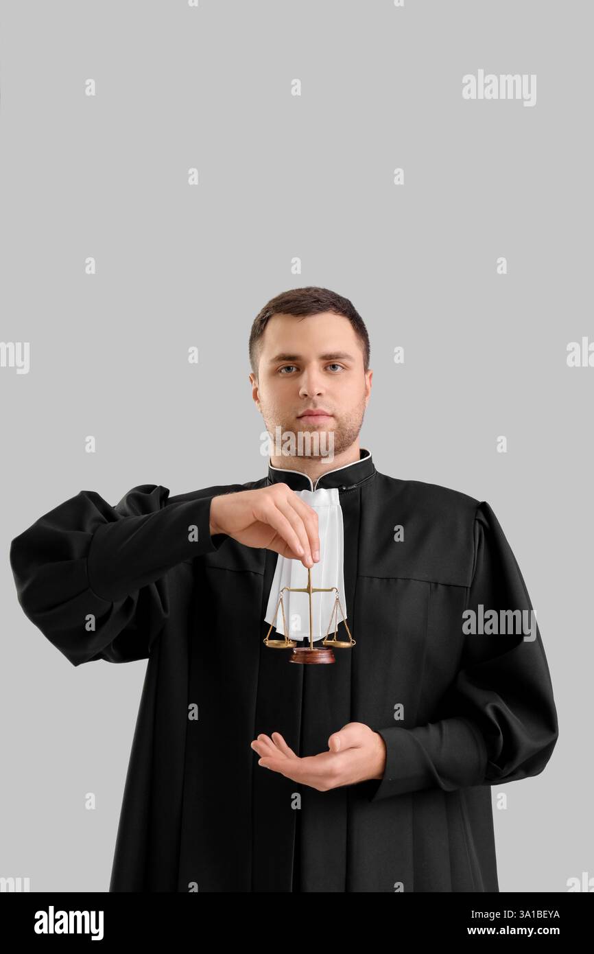 Male judge with justice scales on light background Stock Photo - Alamy