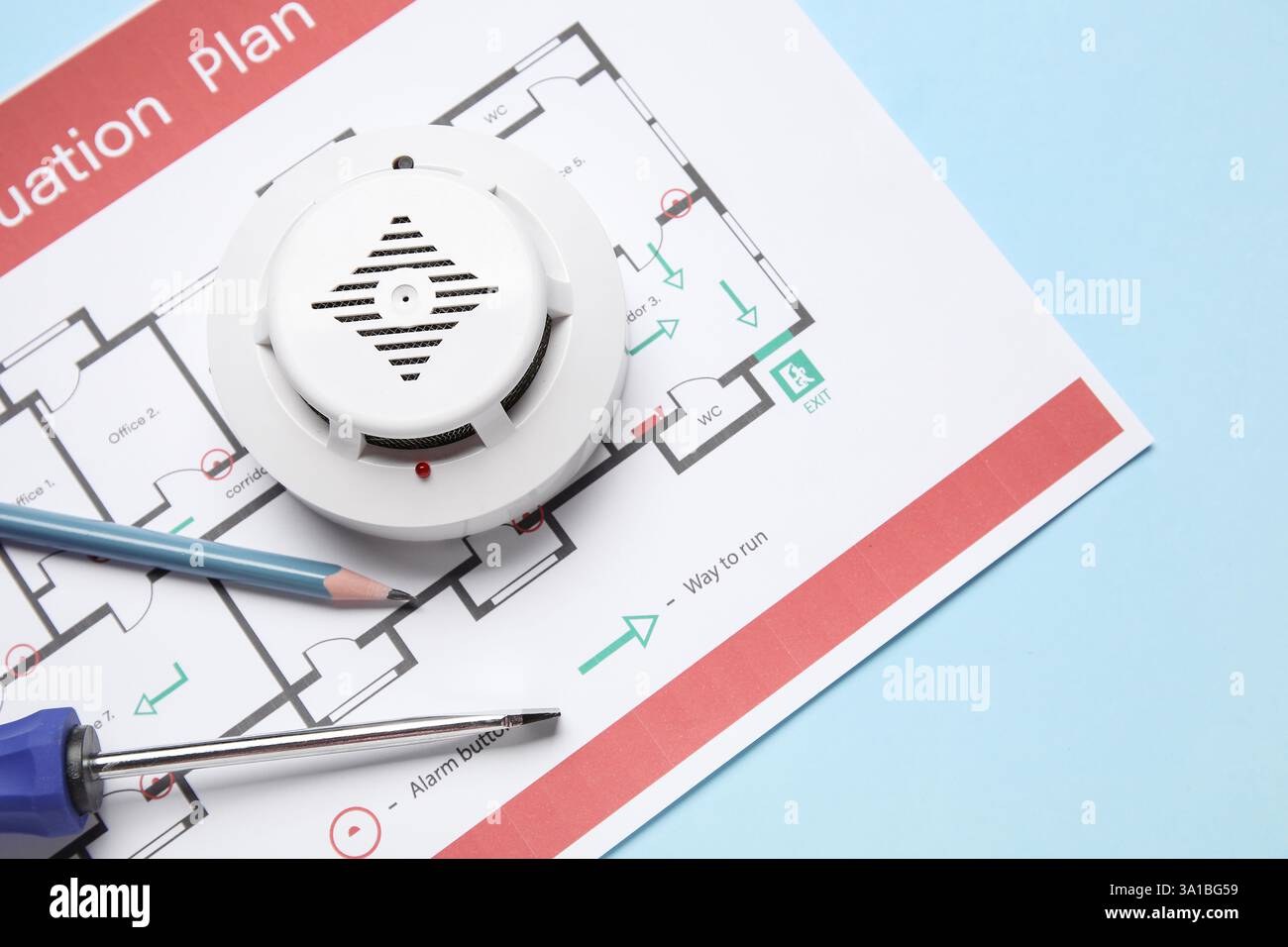 Modern smoke detector with screwdriver, pencil and evacuation plan on ...