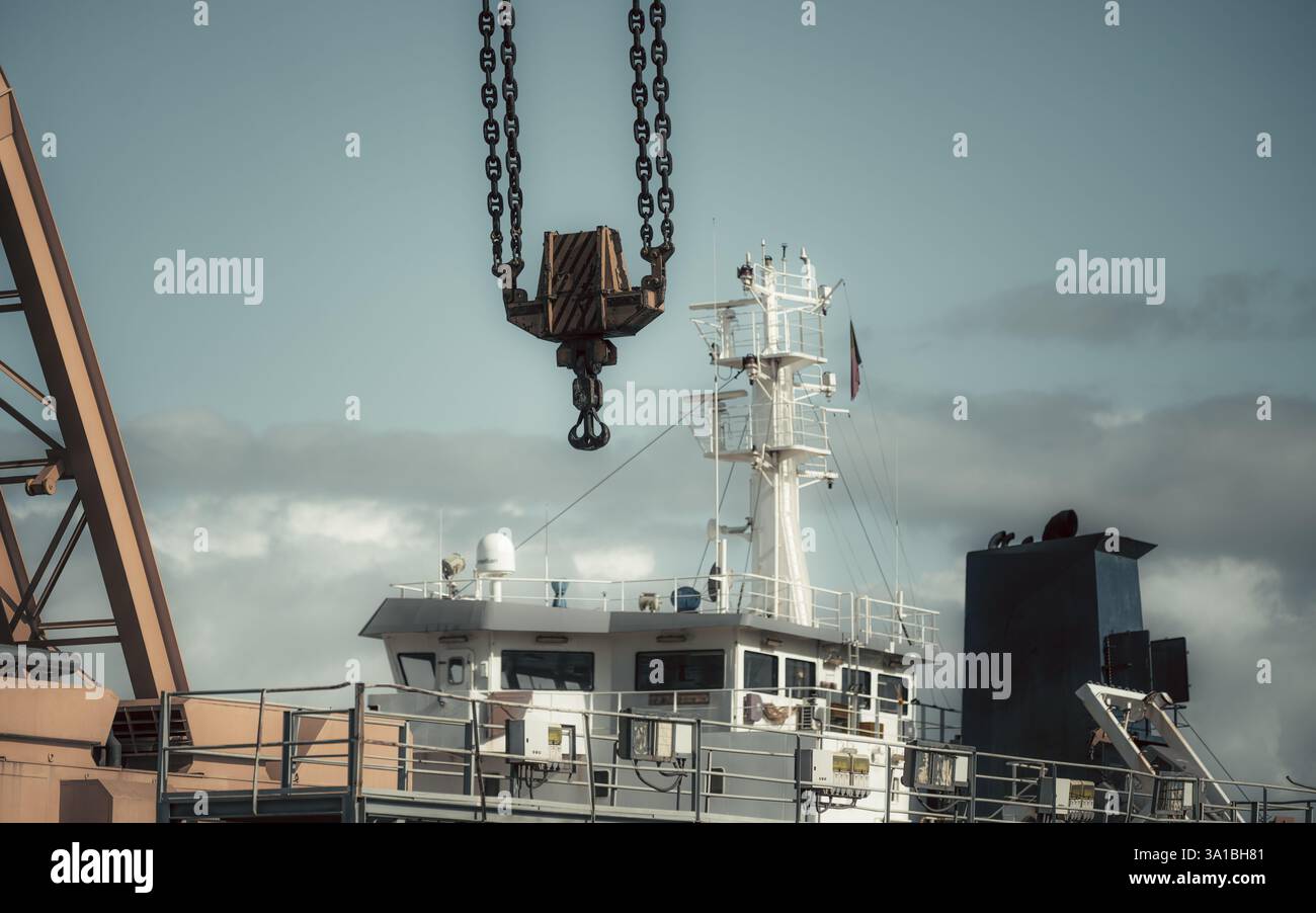 A telephoto shot of an industrial ship crane hook suspended by heavy ...
