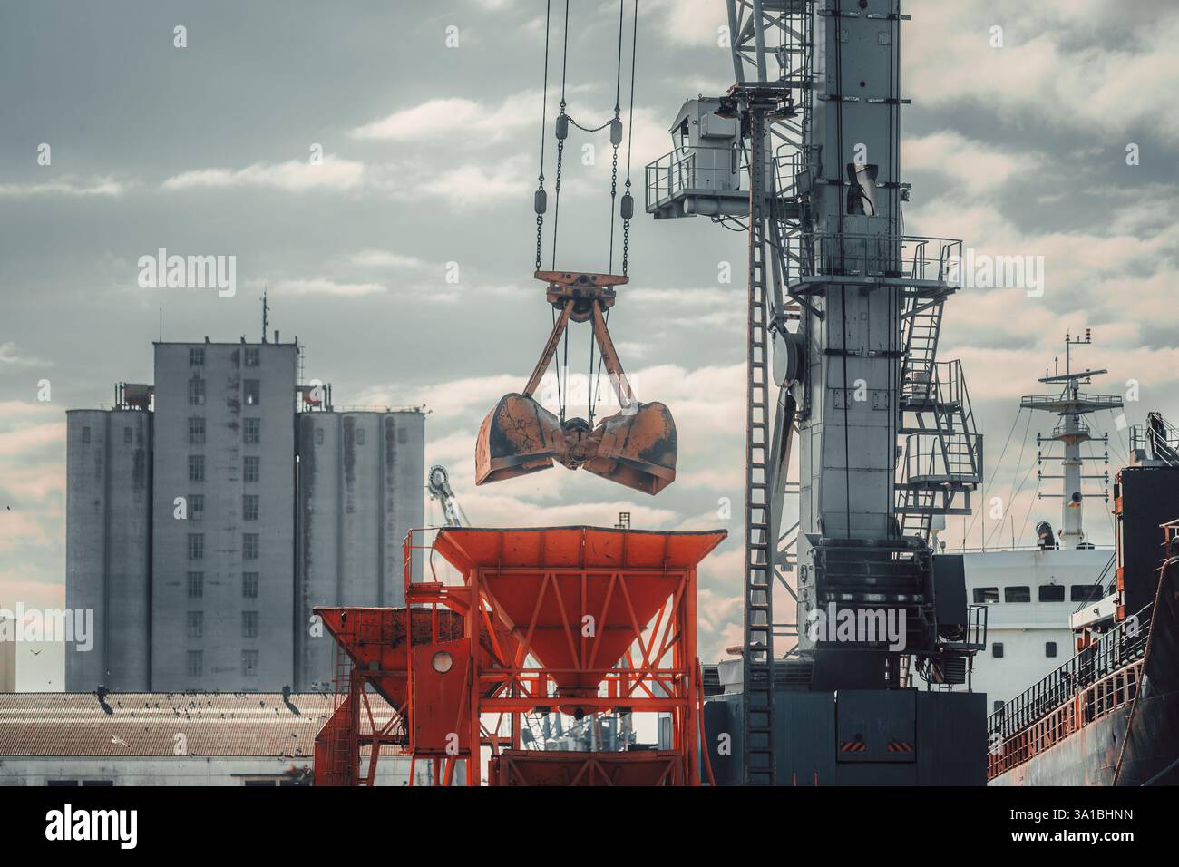Industrial port scene featuring a large orange clamshell grab bucket ...