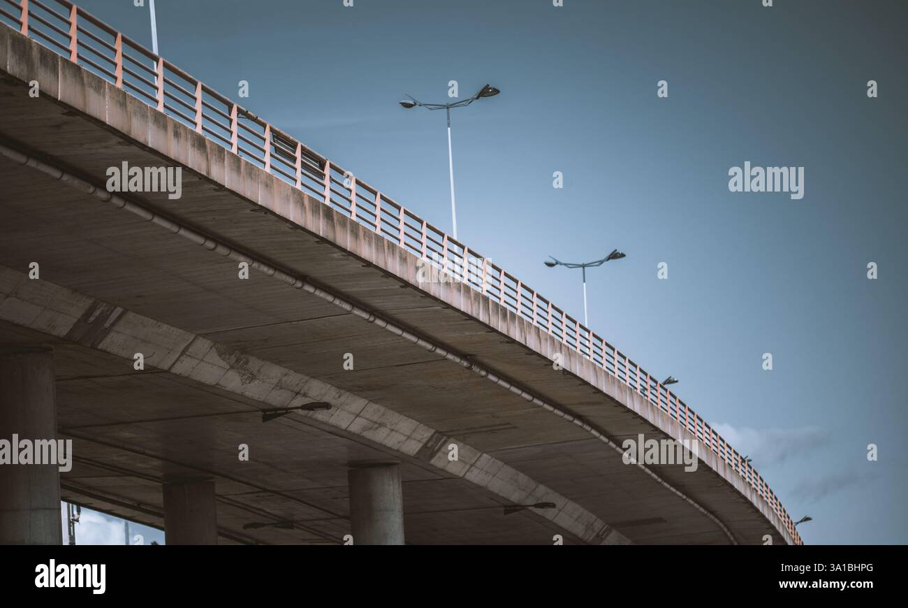 A modern urban overpass with concrete pillars and metal railings ...