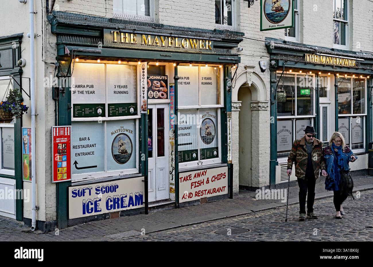 A couple walking in front of The Mayflower public house and restaurant ...