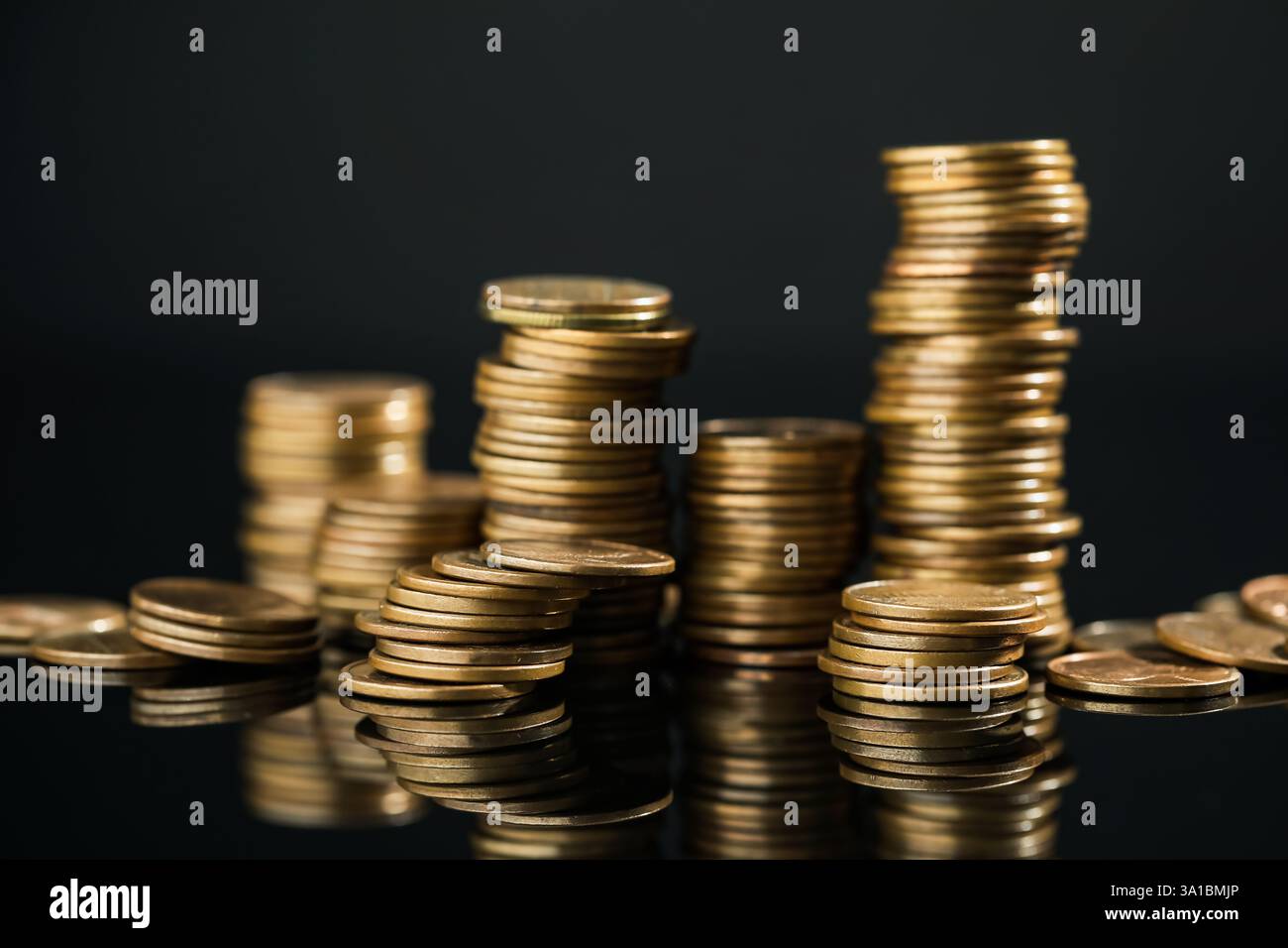 Many stacked coins on dark mirror surface, closeup Stock Photo - Alamy