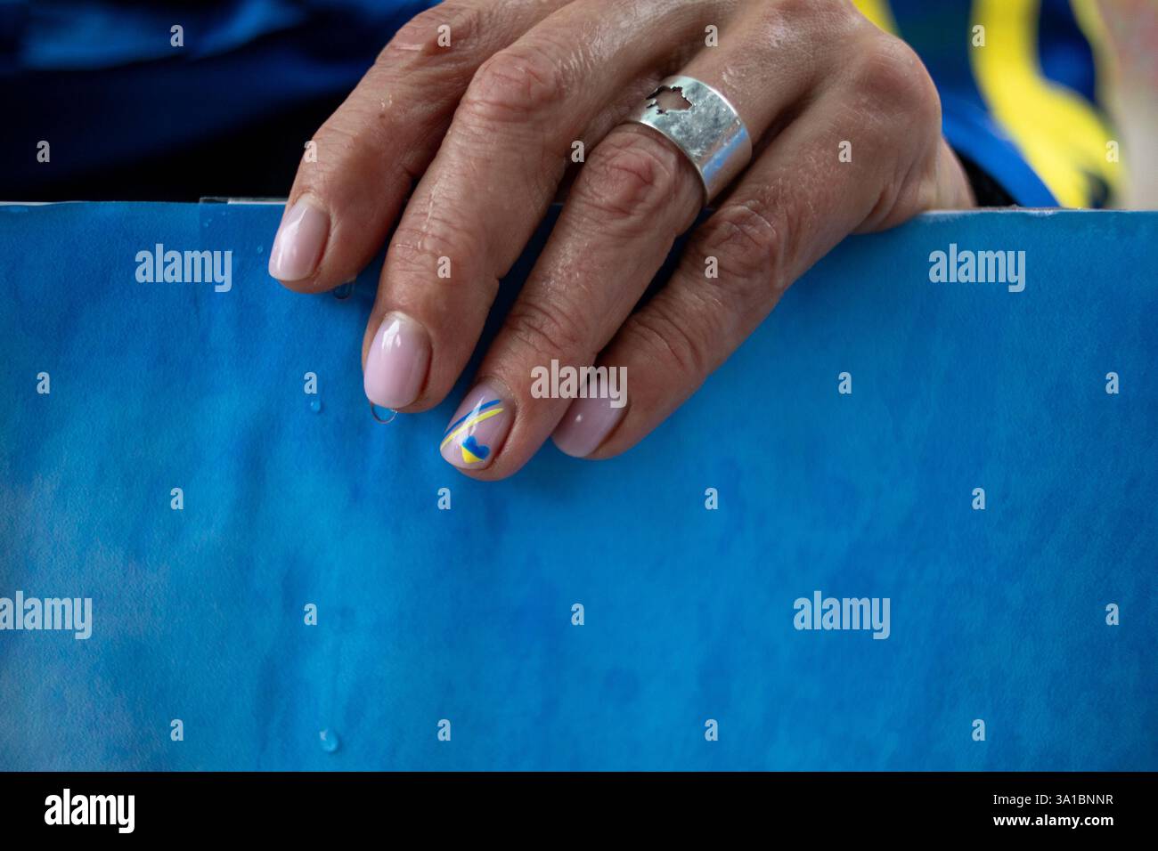 A woman with her nails painted in the colors of the Ukrainian flag seen ...