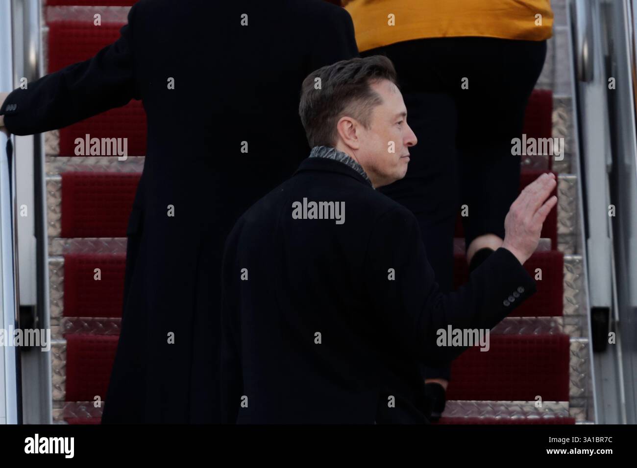 Elon Musk waves as he walks up the stairs of Air Force One upon ...