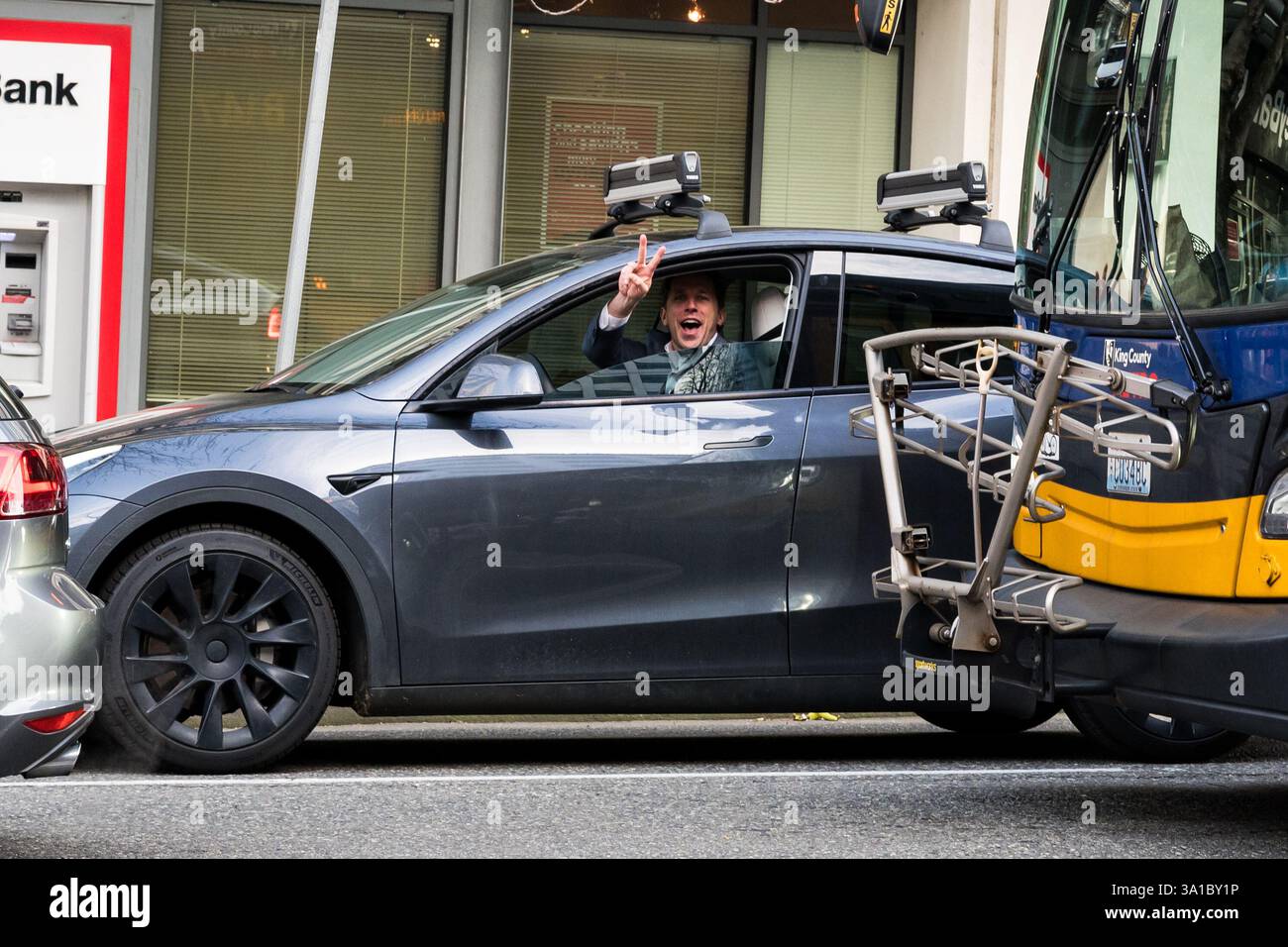 Seattle, USA. 7th Mar 2025. A driver passing by in a tesla holds his ...