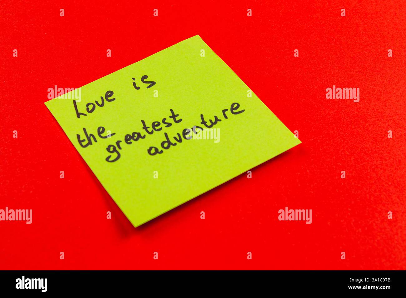 A bright green sticky note with a handwritten message stating love is ...