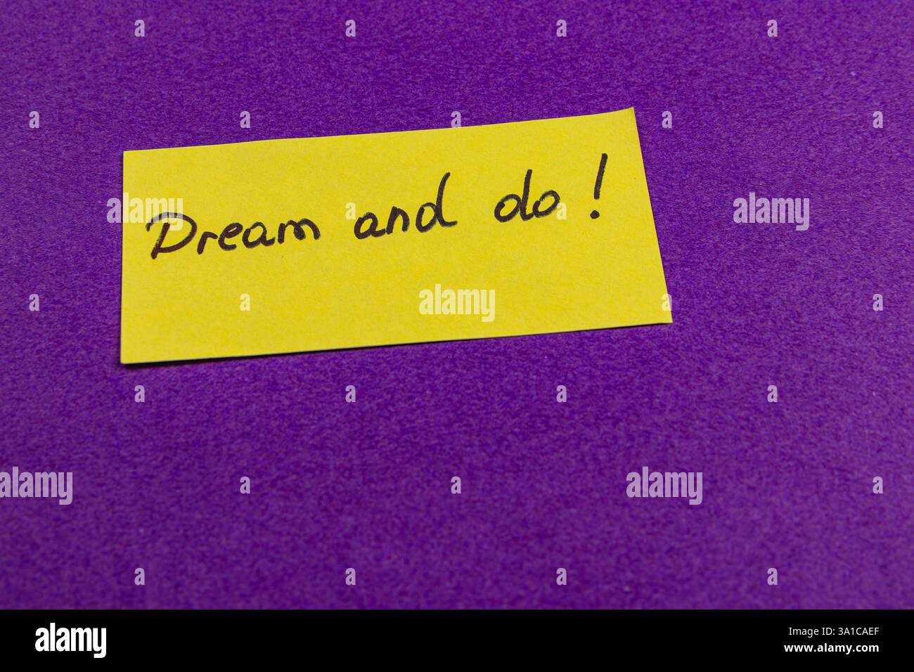 A bright yellow paper with the words Dream and do! handwritten on it is ...