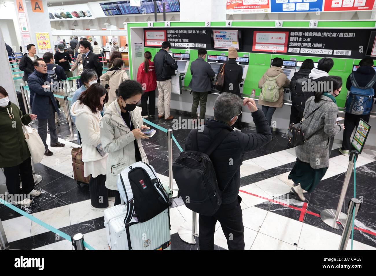 Passengers line up in front of the ticket machine at JR Hakata Station ...
