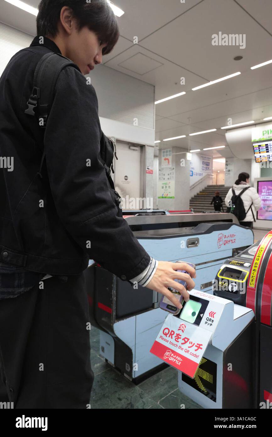 Passengers board trains by holding the QR code displayed on their ...
