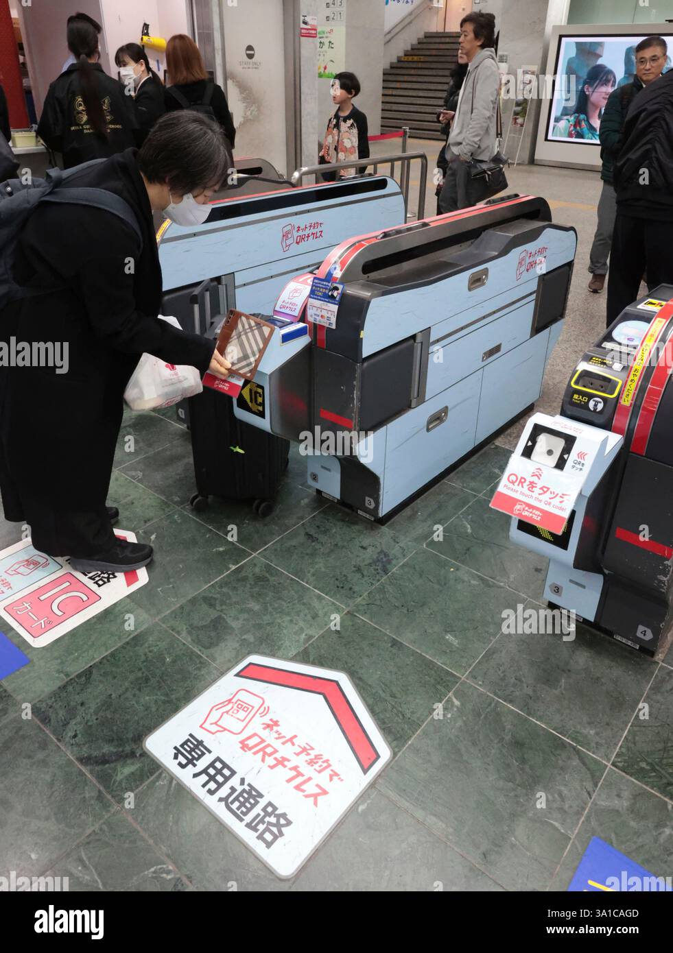 Passengers board trains by holding the QR code displayed on their ...