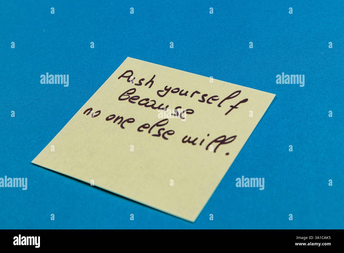 A yellow sticky note rests on a bright blue surface, displaying a ...